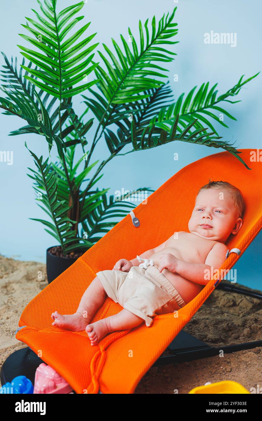 A baby is lying on a recliner chair for babies. Children's recreation ...