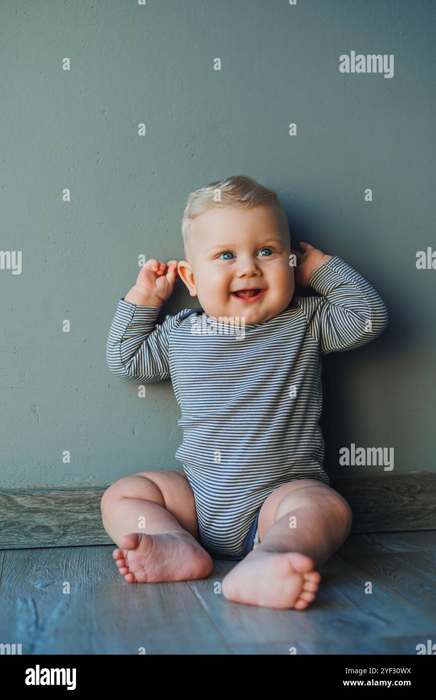 Portrait of a small baby boy in a cotton bodysuit with a smile on his ...