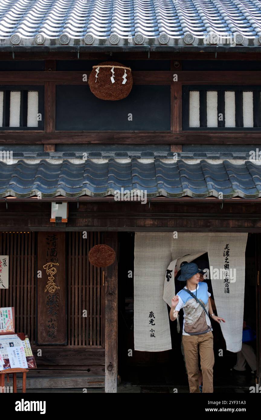 An old sake brewery with a traditional sugidama (cypress ball) hanging ...