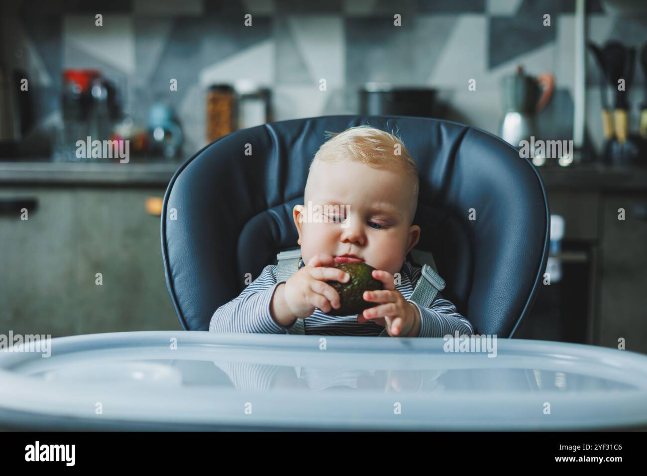 A baby boy eats a delicious avocado. The baby's first meal. The child ...