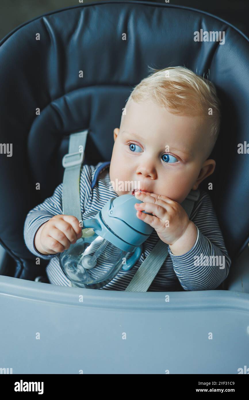 The baby drinks water from a plastic drinking cup with a straw ...