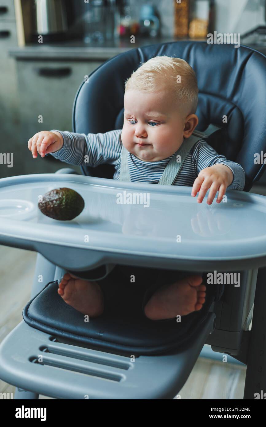 A baby boy eats a delicious avocado. The baby's first meal. The child ...