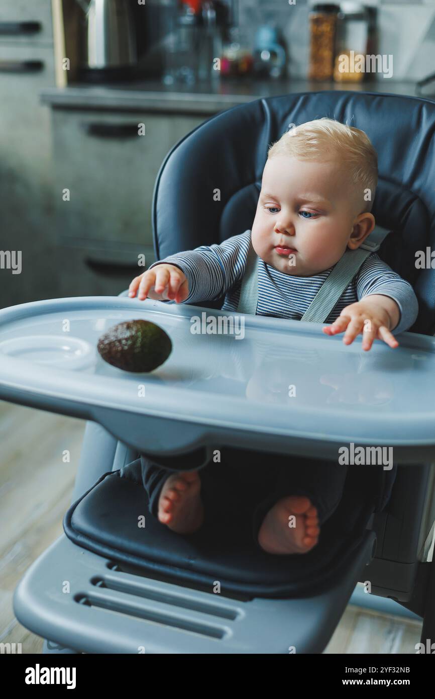 A baby boy eats a delicious avocado. The baby's first meal. The child ...