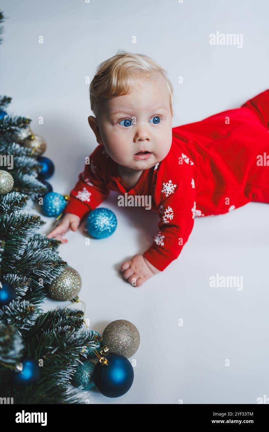 The baby lies near the Christmas tree Children's first Christmas. A ...