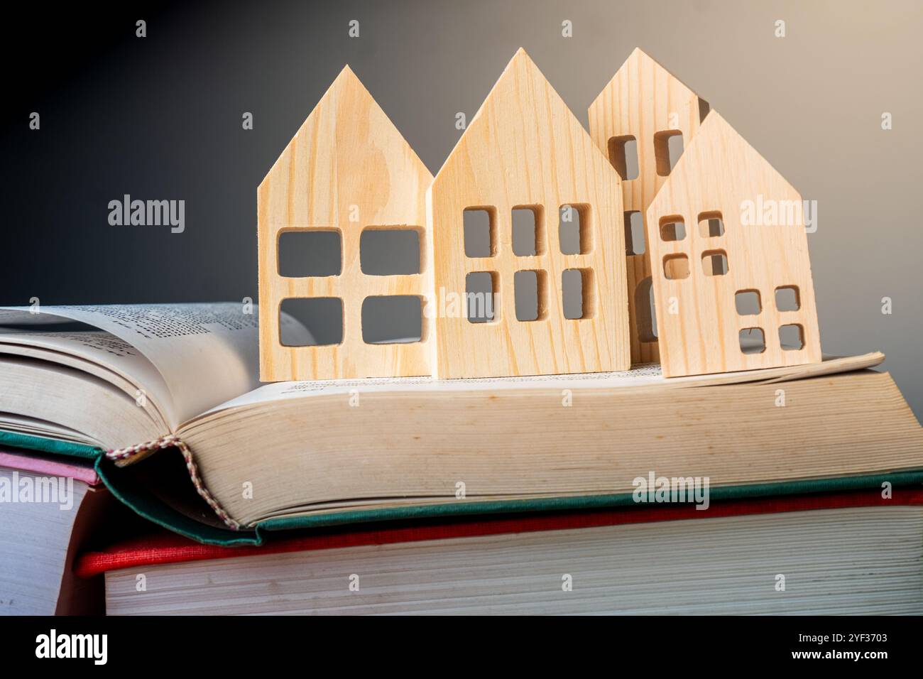 Wooden houses placed on an open book symbolize the theme of education ...