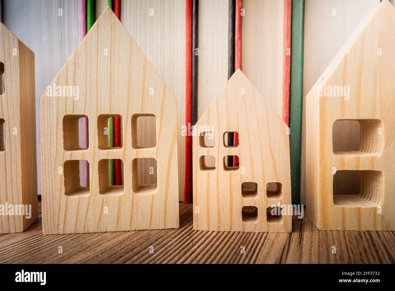 Wooden house models next to stacked books in a cozy study space ...