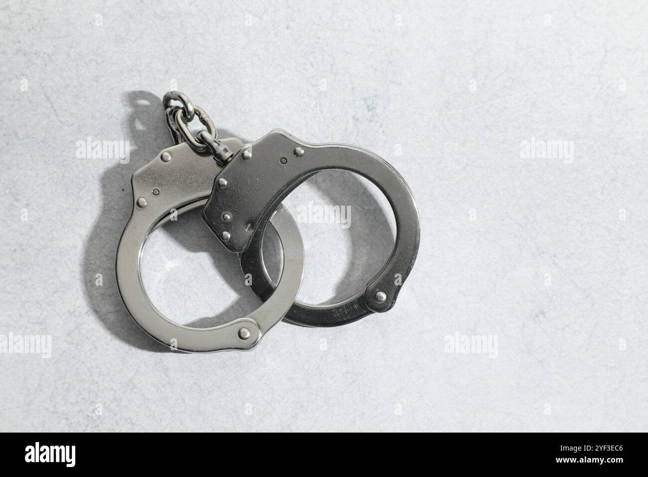 Metal chain handcuffs on light grey table, top view. Space for text ...
