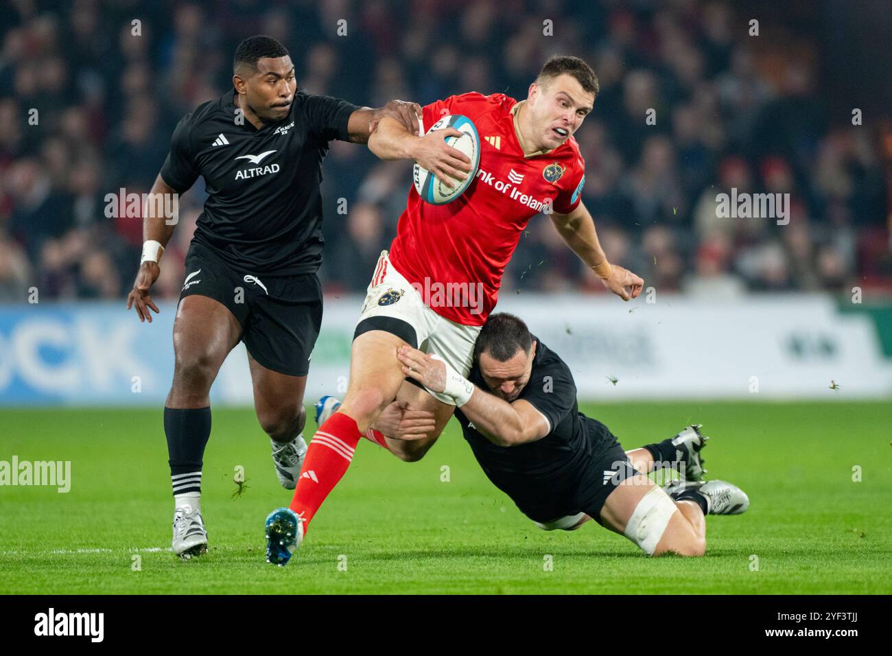 Tom Farrell of Munster tackled by Devan Flanders of All Blacks and Kini ...