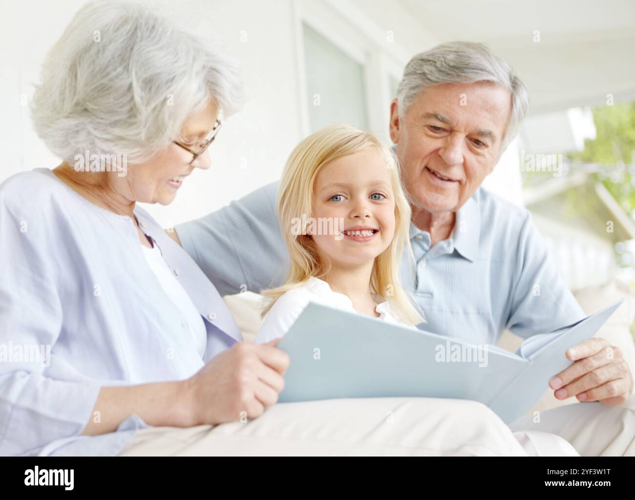 Grandparents, smile and girl reading book in home for learning, bonding ...