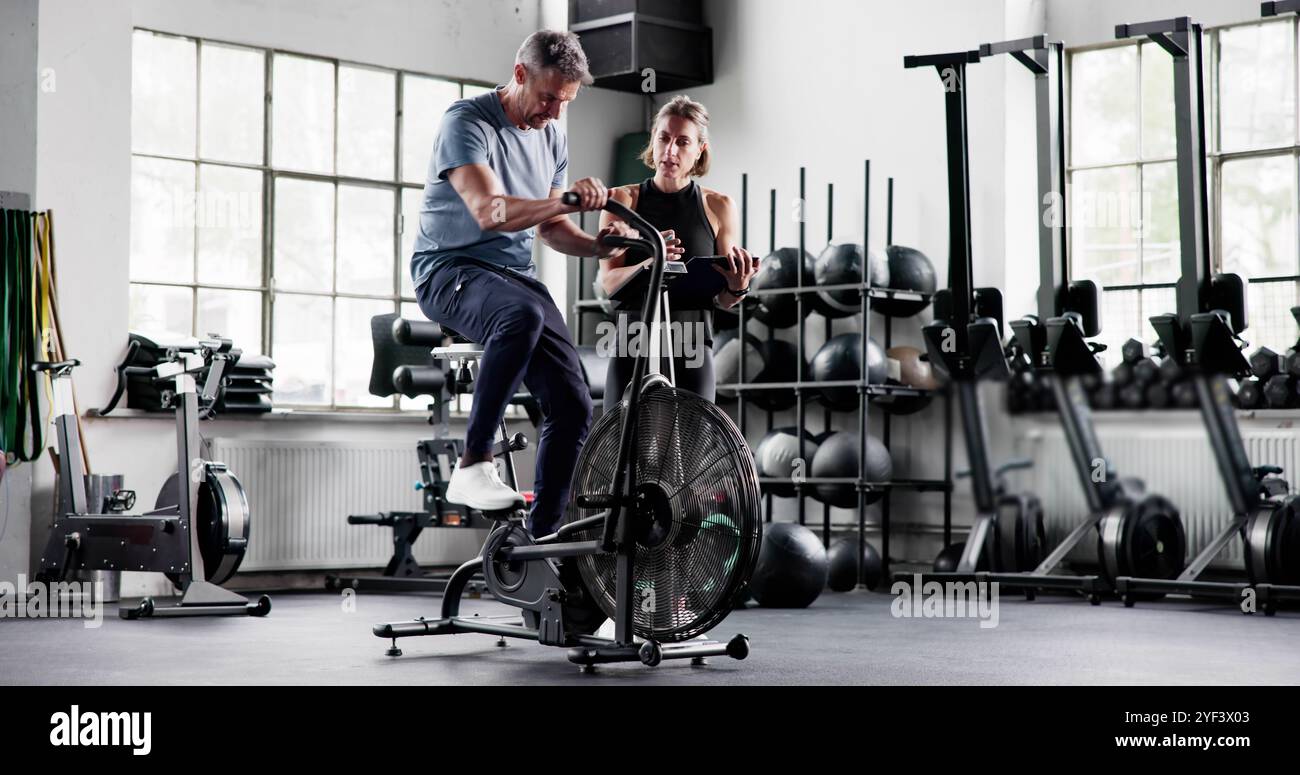 Cardio Workout In Gym On Elliptical Bike Machine With Personal Trainer ...