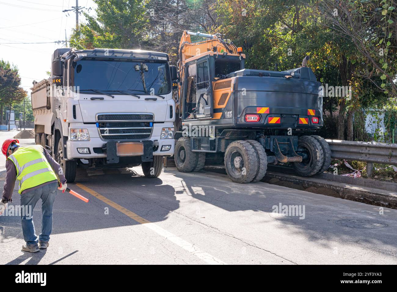 repairing a road using a backhoe and truck Stock Photo - Alamy