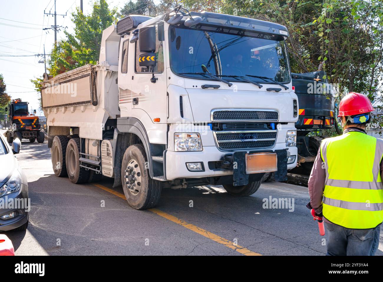 repairing a road using a backhoe and truck Stock Photo - Alamy