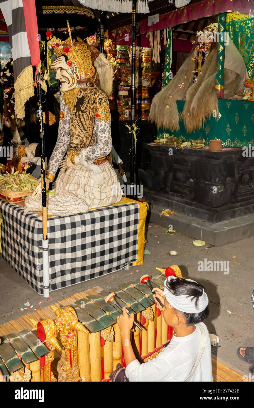 A boy playing rindik at Kuningan ceremony, Rangda and Barong Landung ...