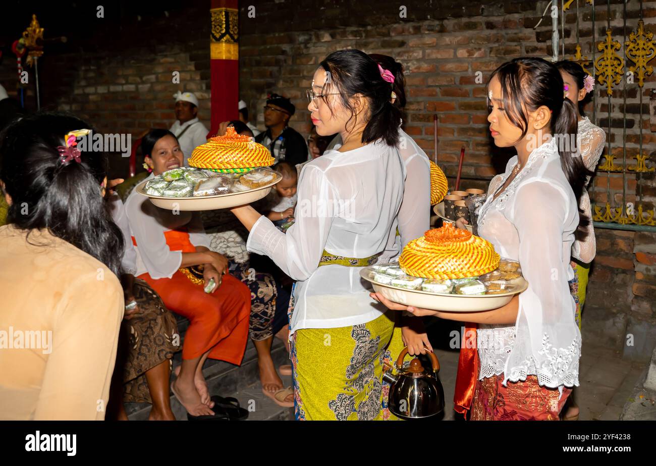 Balinese girls serving food on tray to the members of the community at ...