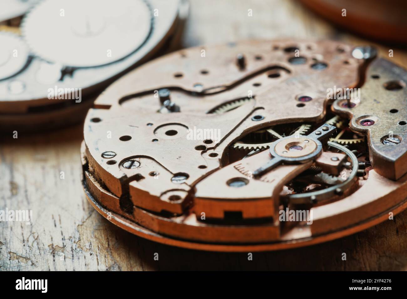 Resting on the workbench, these watch movements exhibit a complex ...