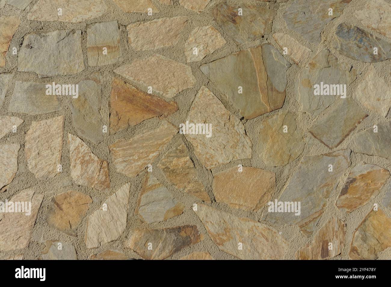 A textured wall adorned with various shapes of natural stones in earthy ...