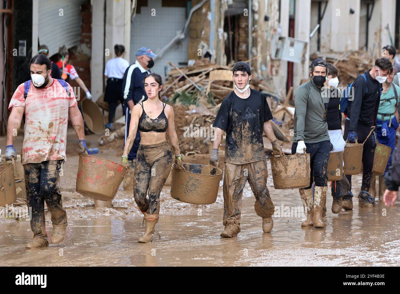 Volunteers carry buckets of mud after floods in Paiporta, Spain, Sunday ...