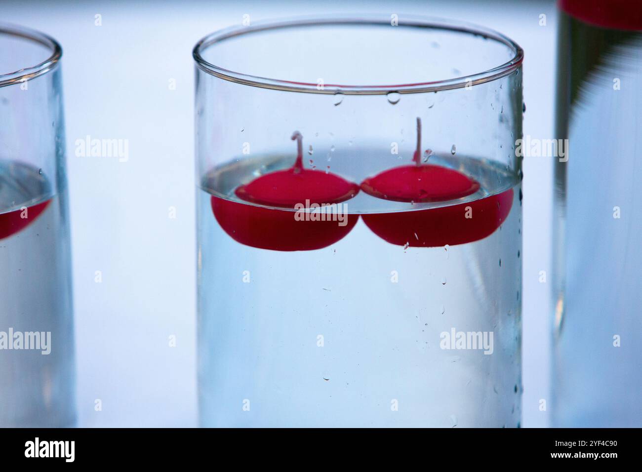 Two red floating candles in a glass of water create a romantic ...