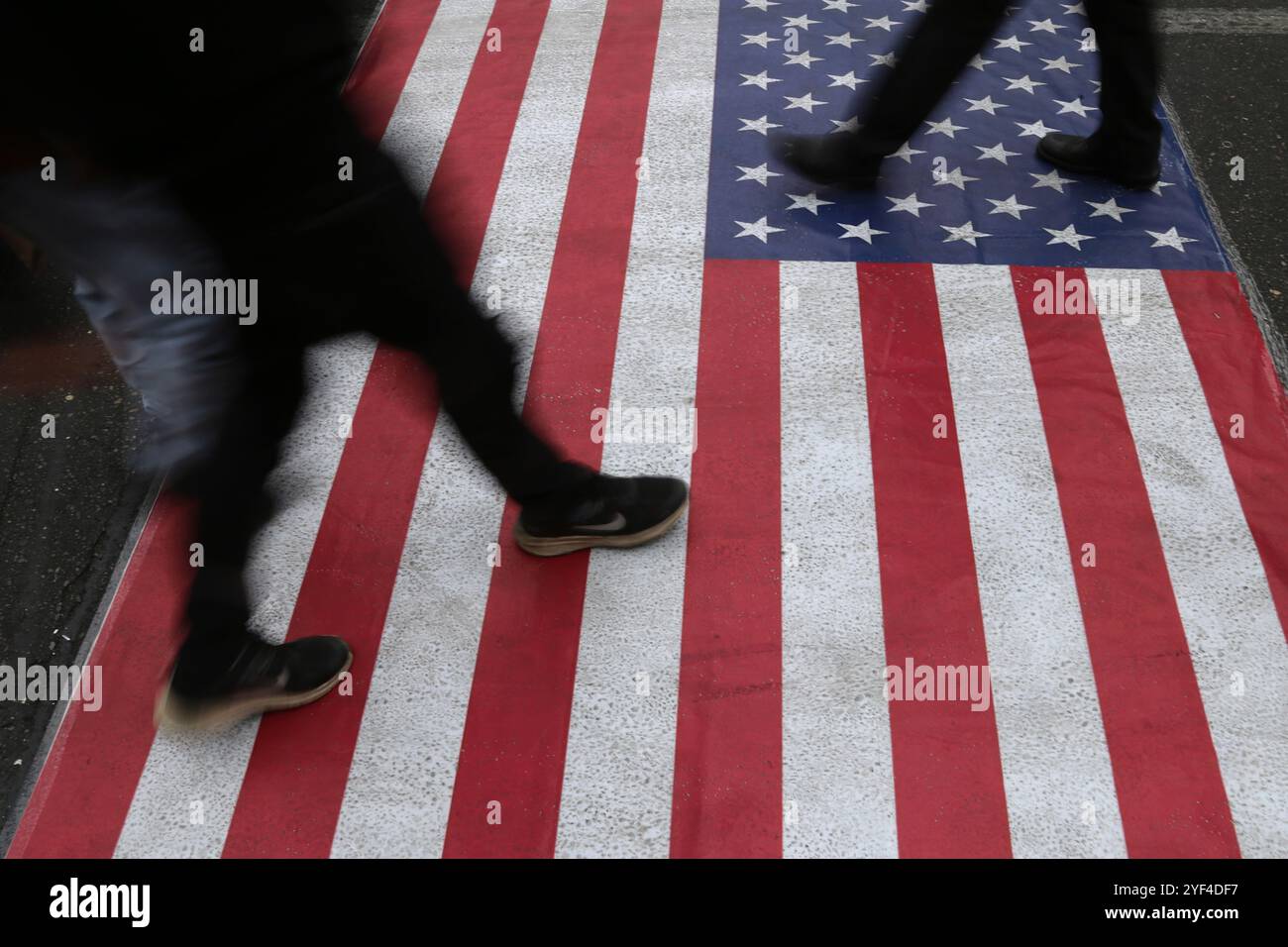 November 3, 2024, Tehran, Iran: People walk over a US flag during an ...