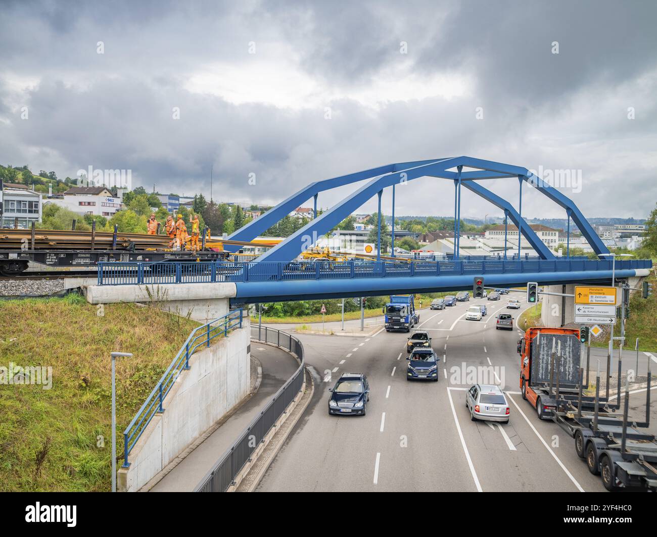 Blue painted bridge with construction workers and passing traffic ...