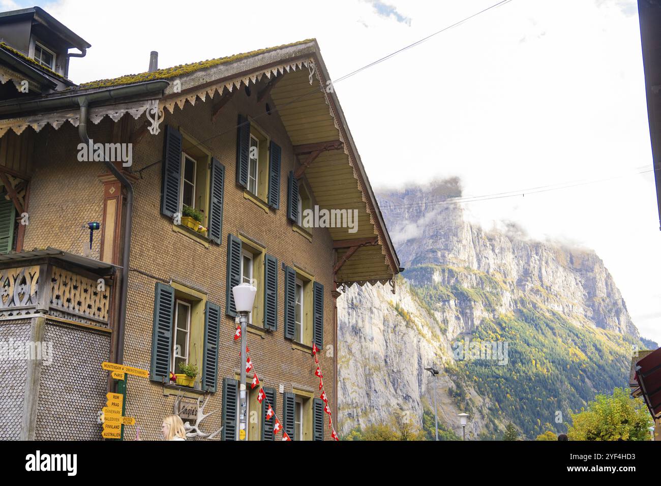 Traditional Swiss house in front of a mountain backdrop, surrounded by ...