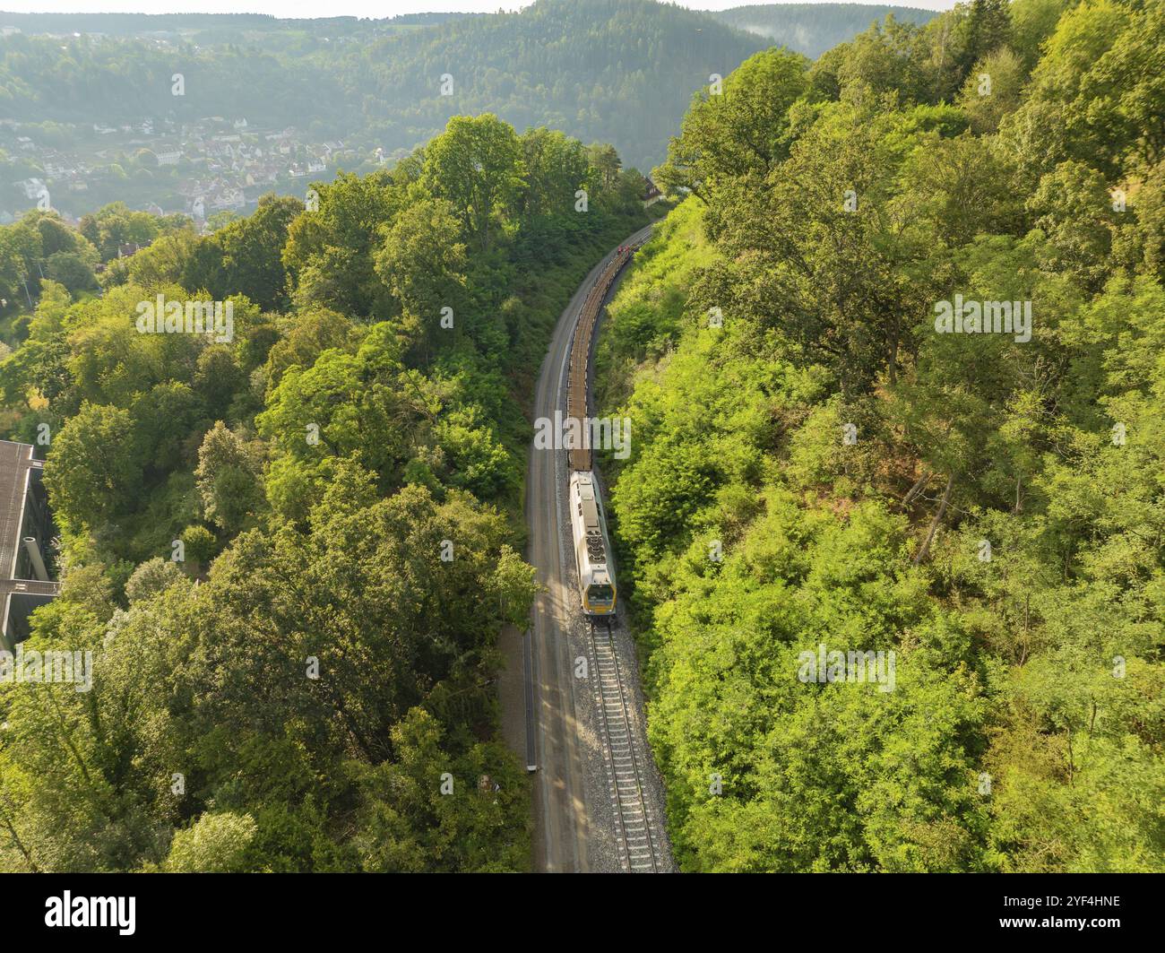 Train travelling through green hilly forest landscape, track ...
