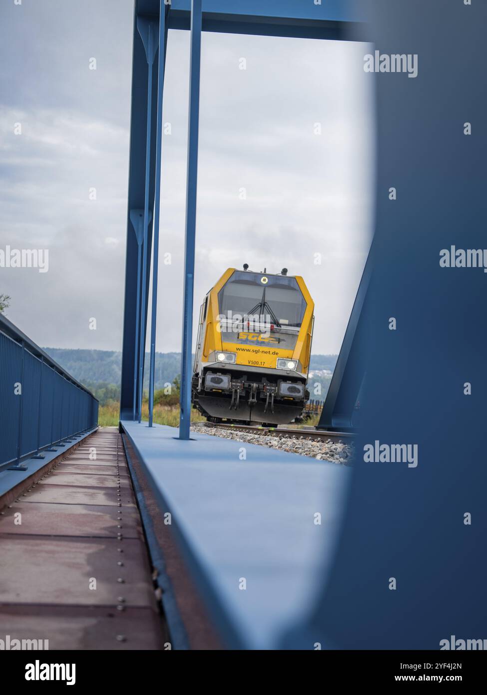 Train approaching from behind blue subway on rails, track construction, rail delivery for ...