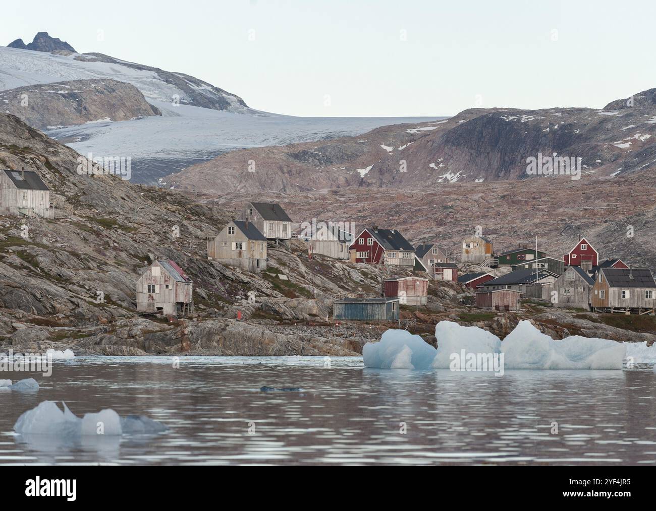 Icebergs in front of wooden houses in the Inuit settlement of ...