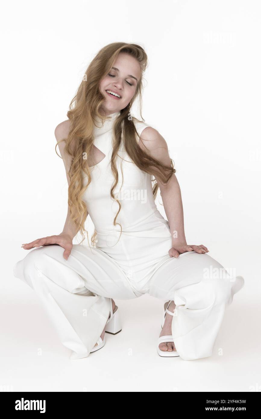 Smiling young woman with eyes closed sitting squatting position put ...