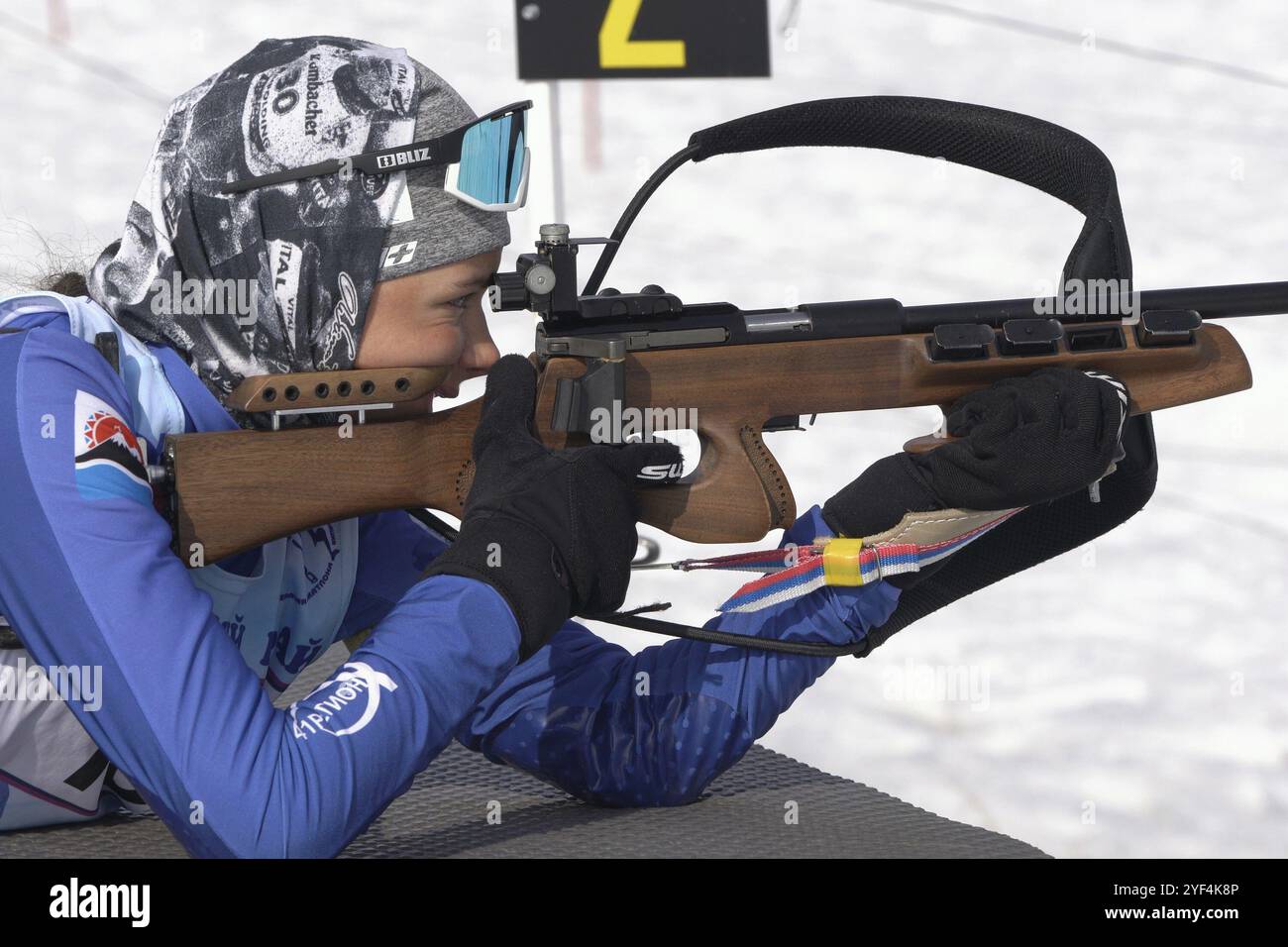 Sportswoman biathlete aiming, rifle shooting prone position. Biathlete ...