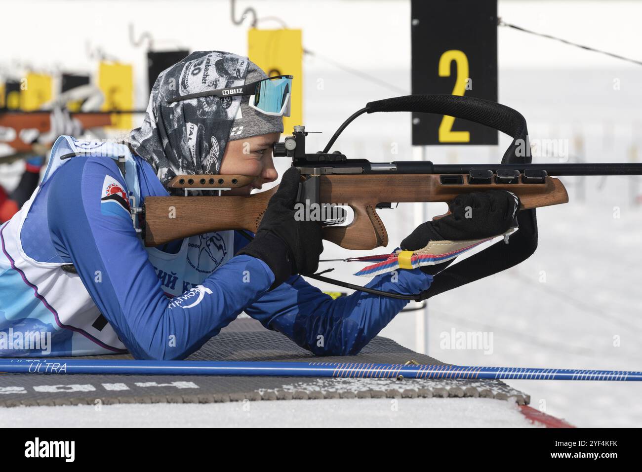 Sportswoman biathlete aiming, rifle shooting in prone position ...