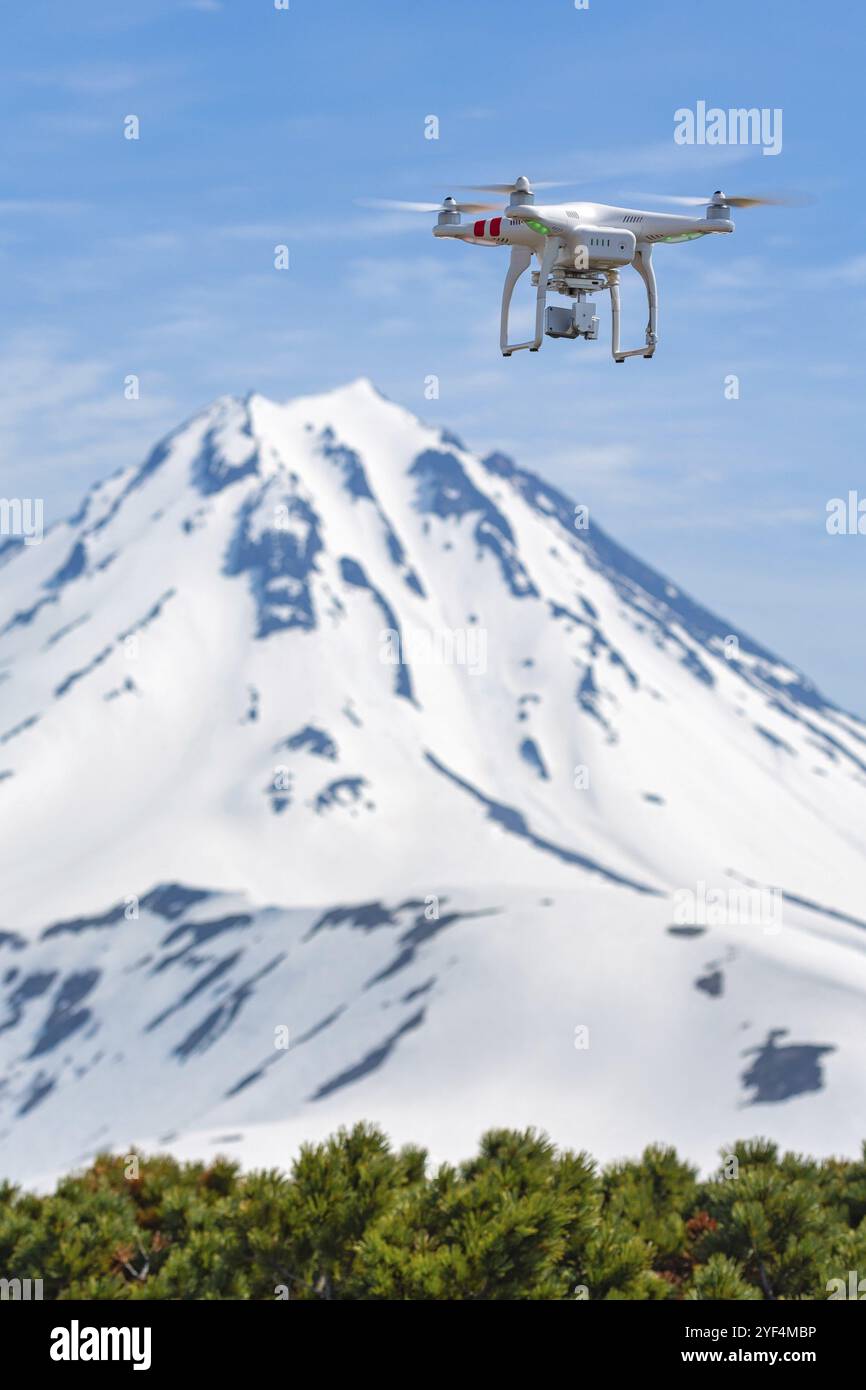 Tech drone quadcopter UAV flying in blue sky on background rocky ...