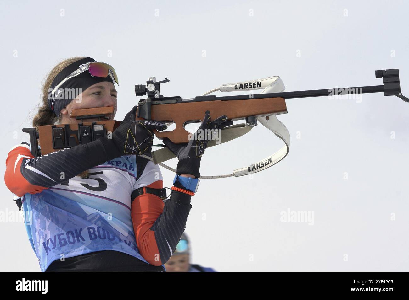 Sportswoman biathlete aiming, rifle shooting, reloading in standing ...
