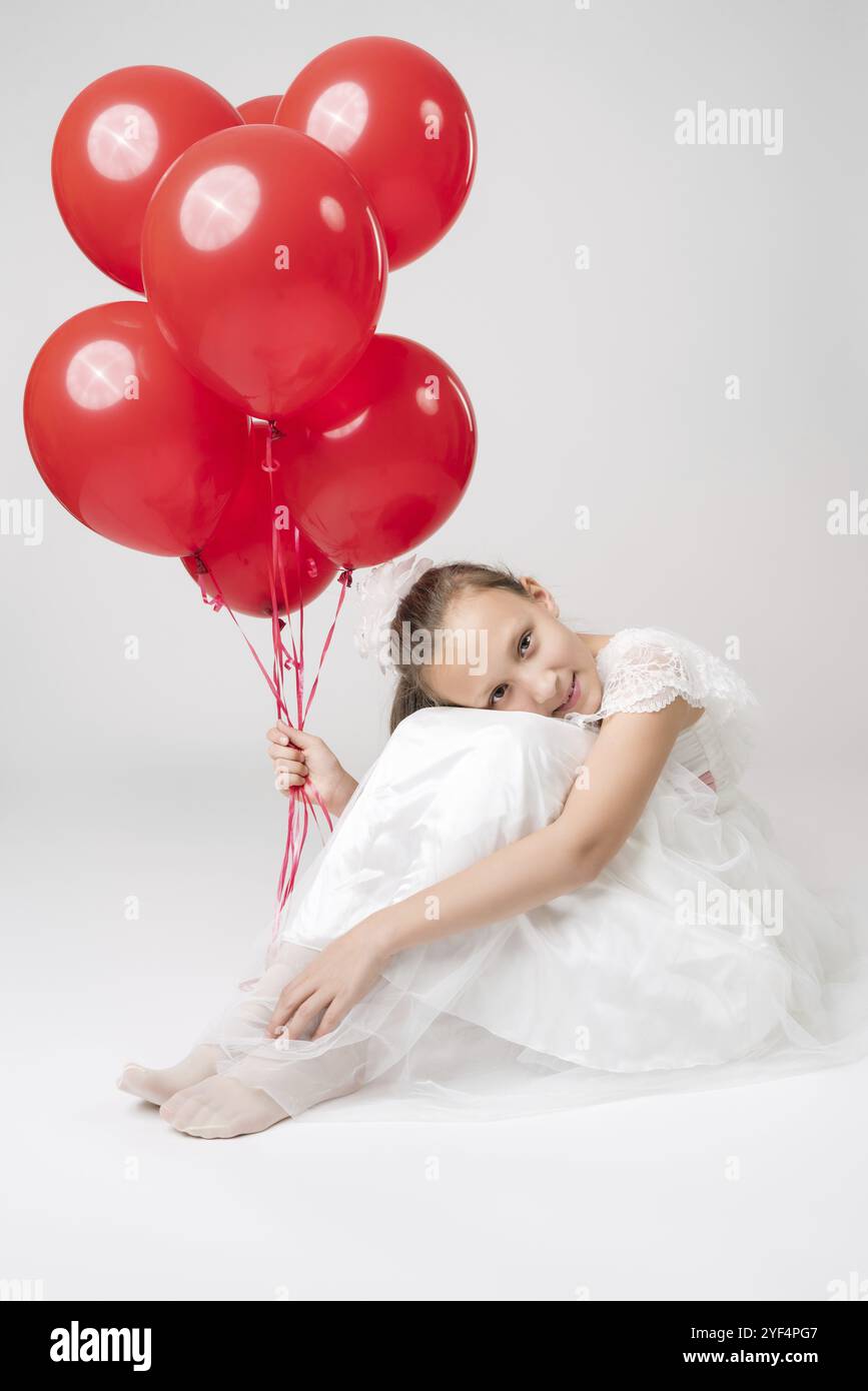 Romantic girl in white dress holding lot of red balloons in hand, put ...