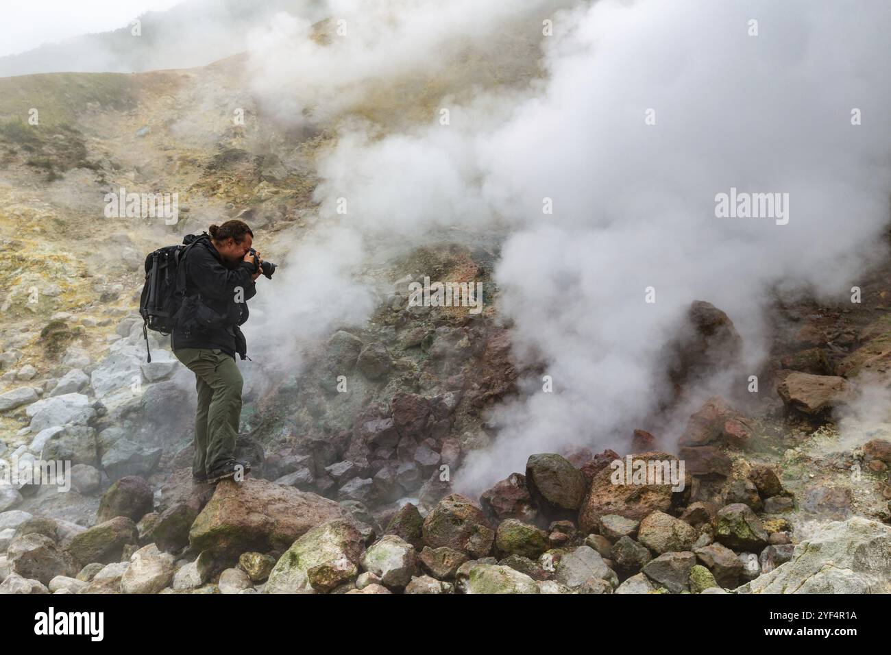 Male photographer takes pictures of aggressive volcanic landscape, hot ...