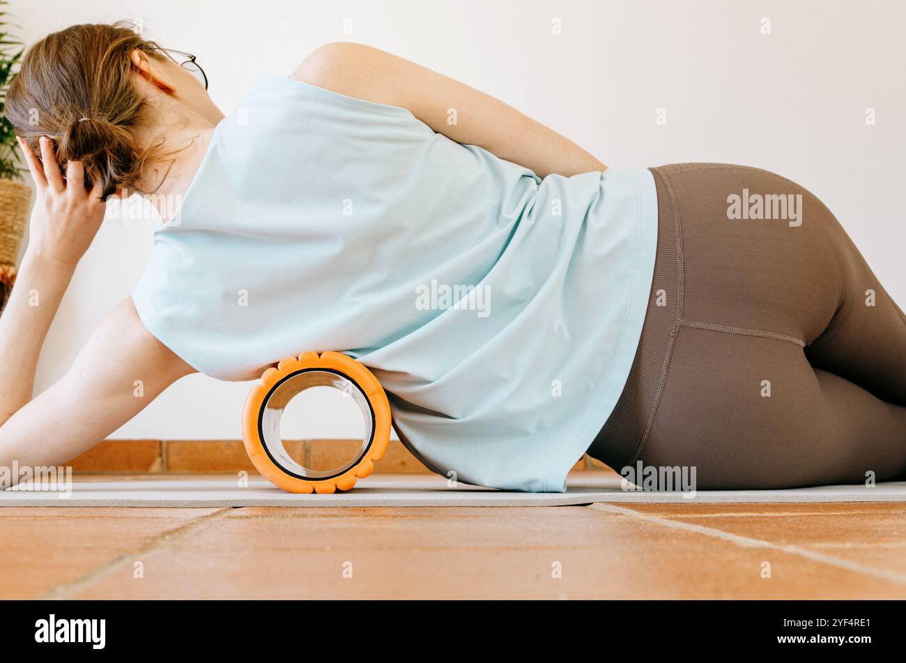 Woman rolling lower armpit on massage foam roller to release tension in ...
