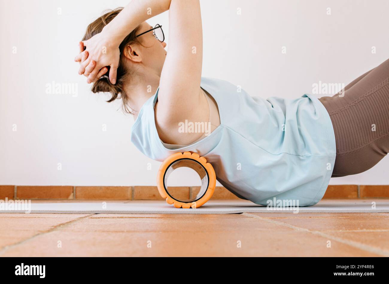 Woman rolling back on a foam massage roller to release tension in back ...