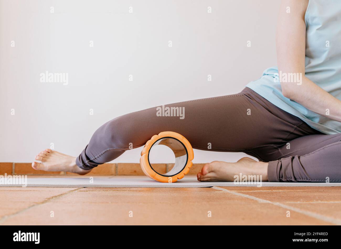 Woman doing self myofascial release of inner thigh with foam roller ...
