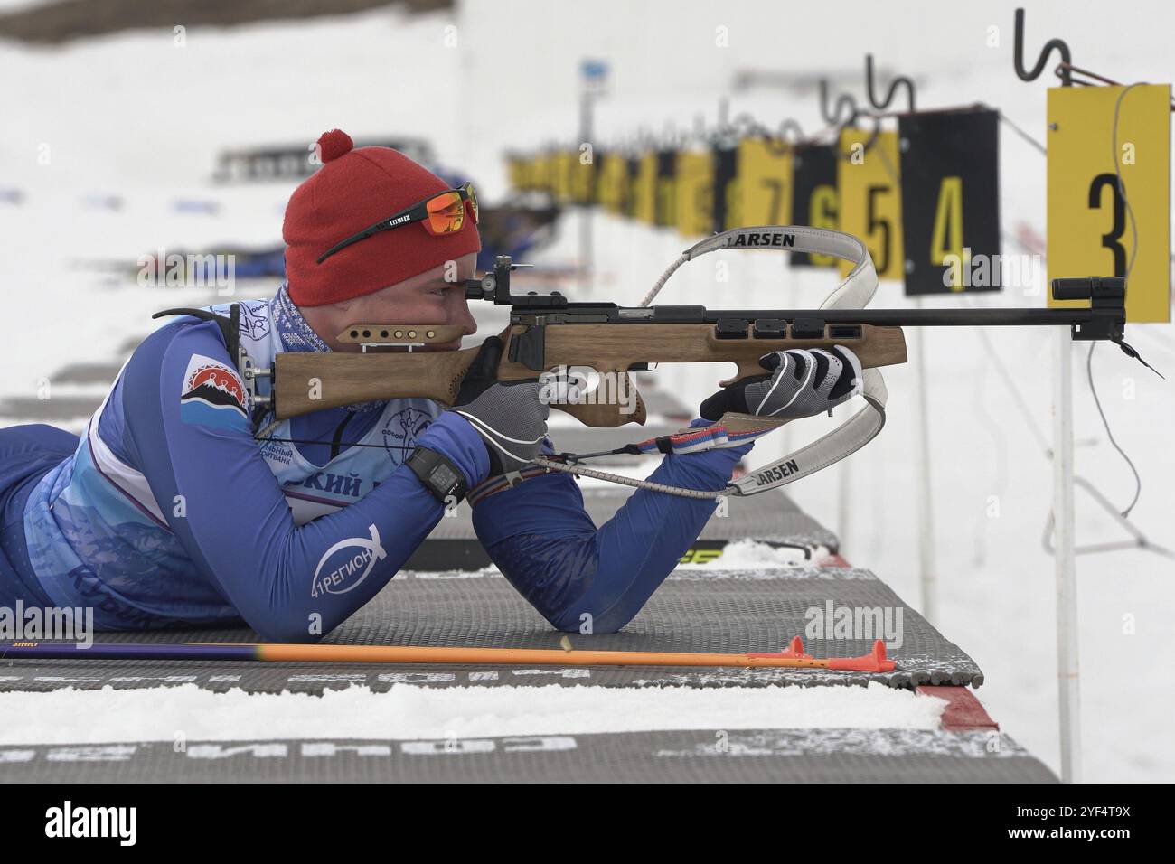 Sportsman biathlete rifle shooting in prone position. Biathlete Leonid ...