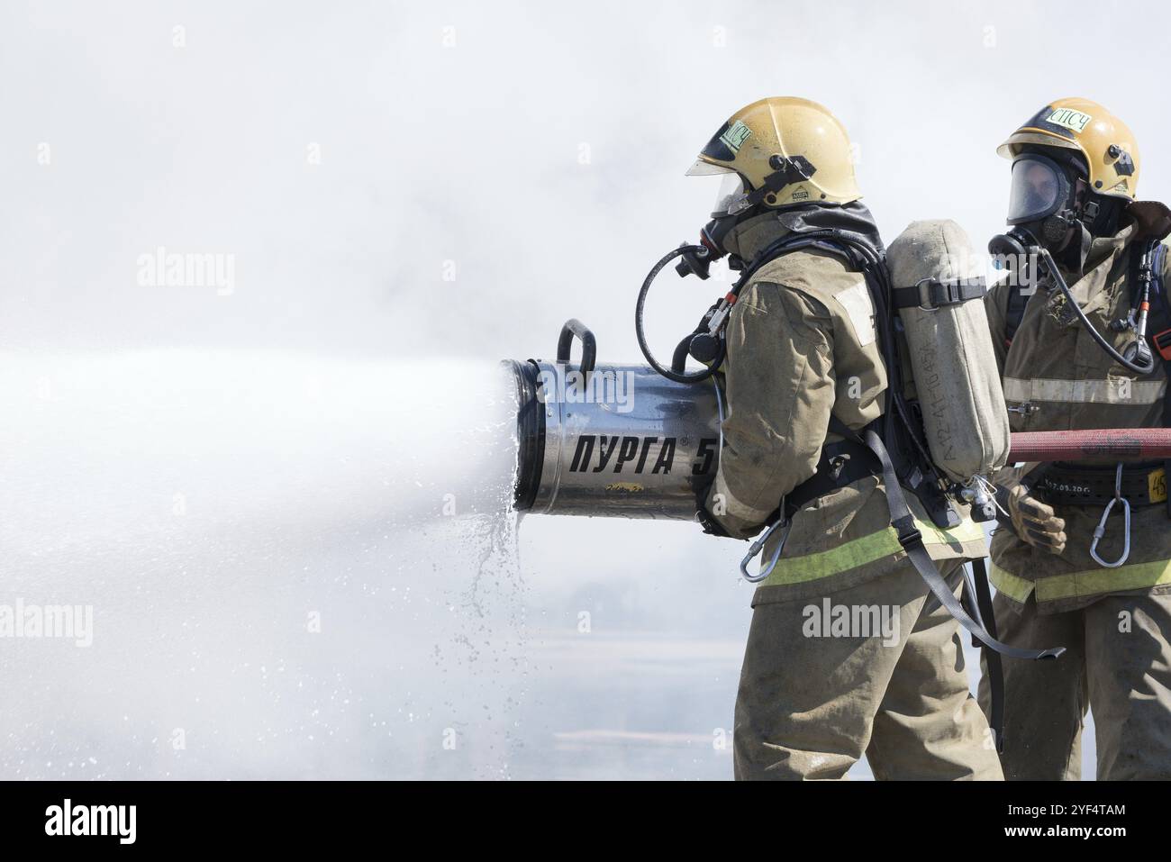 Two firefighters extinguish fire from fire hose, using firefighting ...