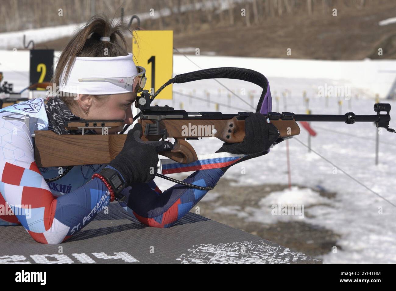 Sportswoman biathlete aiming, rifle shooting prone position. Biathlete ...