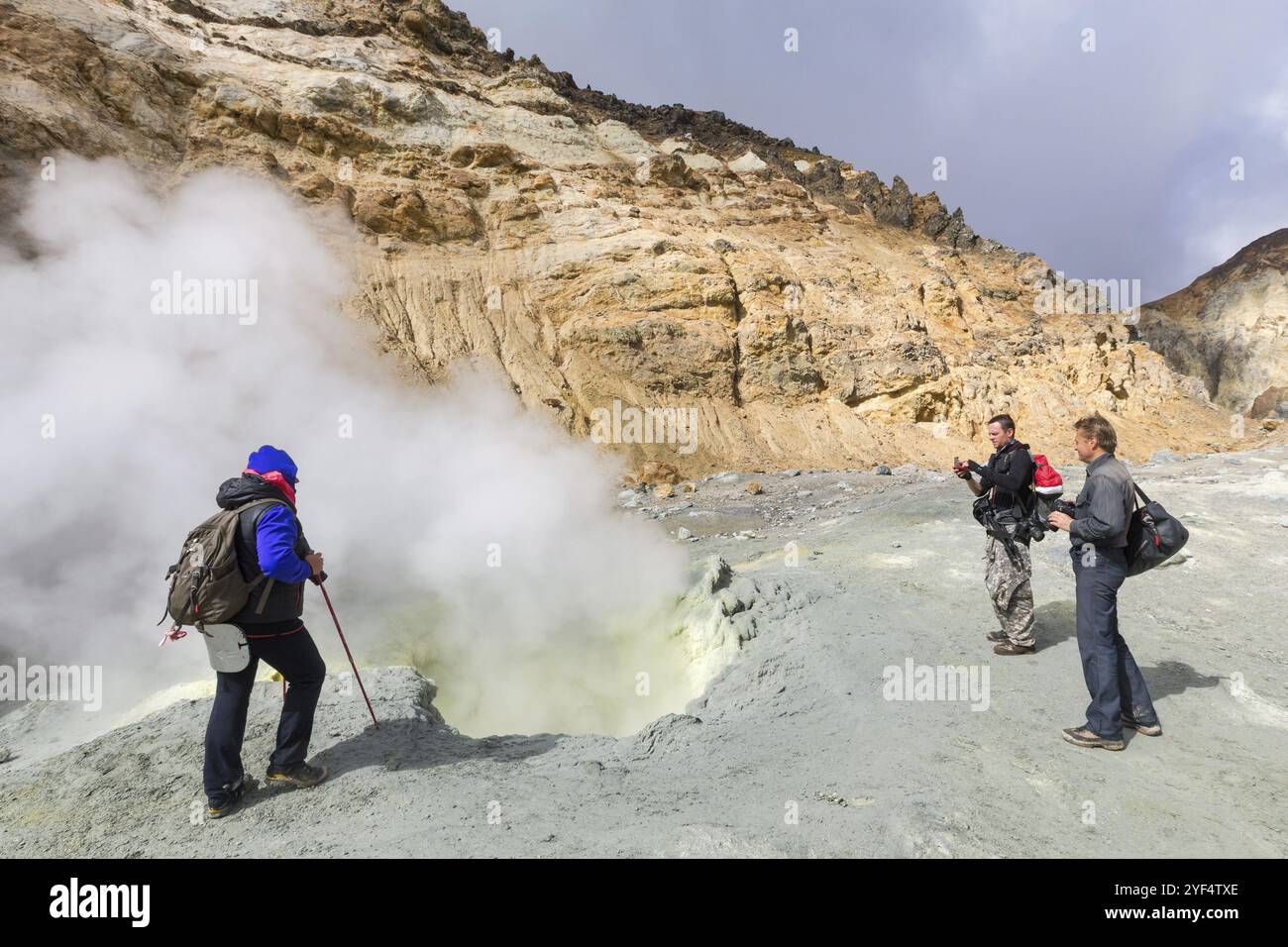 Group tourists watching eruption of hot springs, fumes fumarole ...