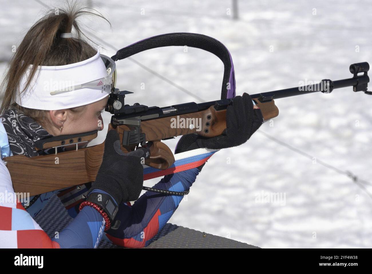 Sportswoman biathlete aiming, rifle shooting in prone position ...