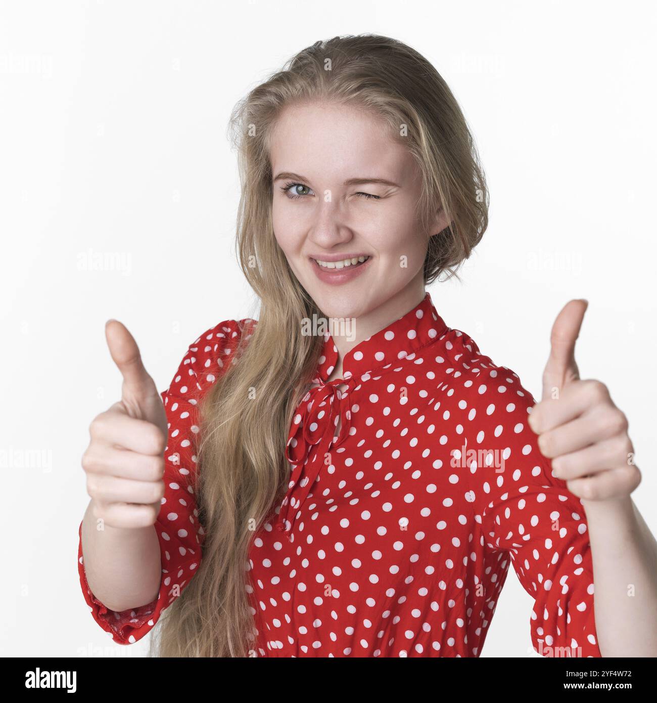 Happy smiling blonde young woman playfully closed one eye and shows ...