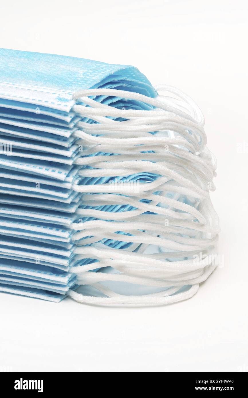 Stack of blue medical surgical face masks with ear straps on white ...