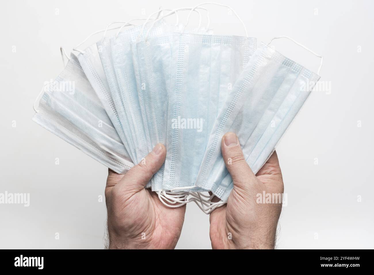 Male patient holding lot medical face mask in hands on white background ...