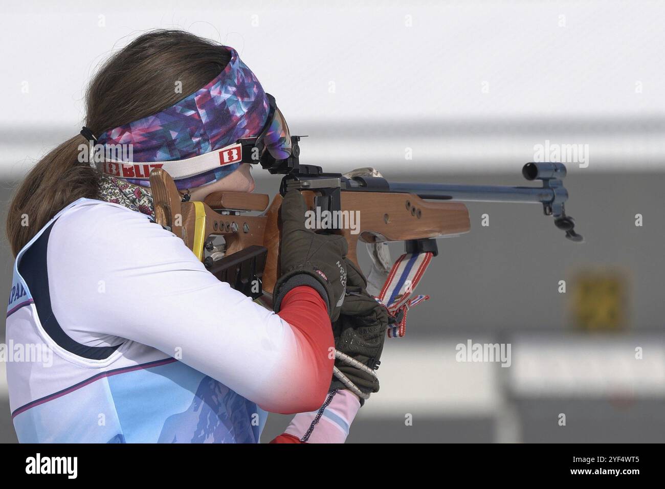 Sportswoman biathlete aiming, rifle shooting standing position ...