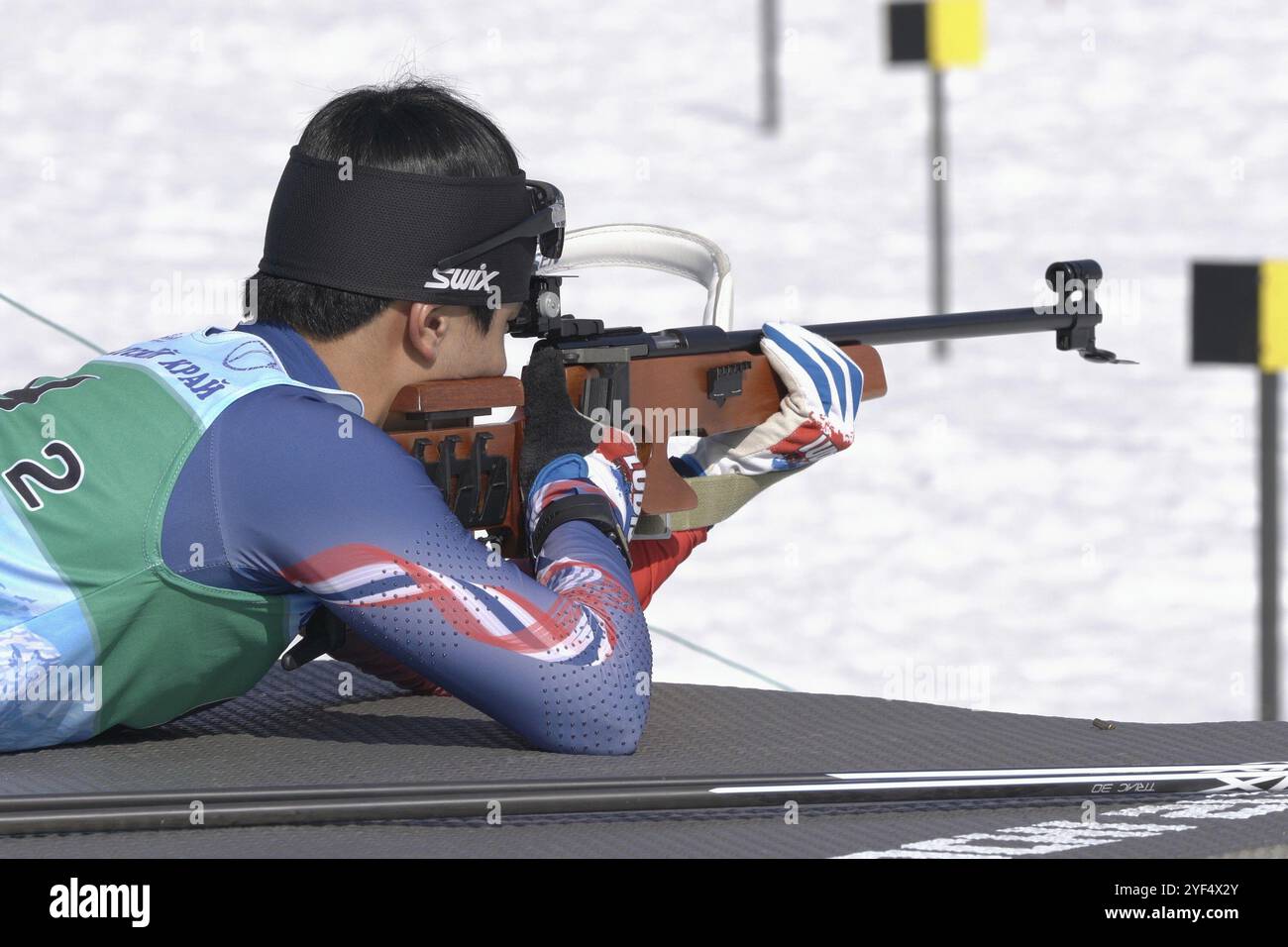 Sportsman biathlete aiming, rifle shooting, reloads in prone position ...