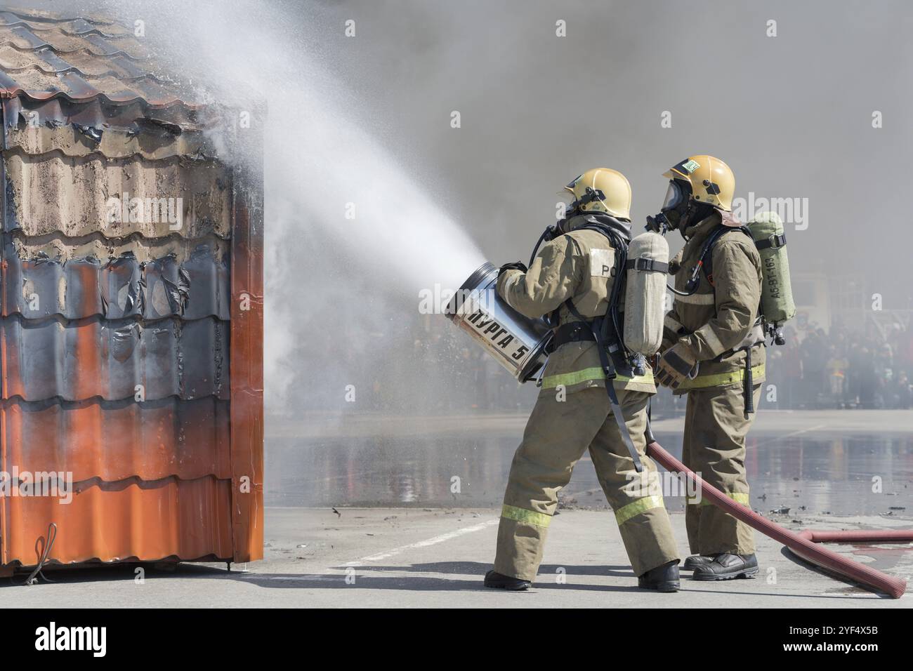Two firefighters extinguishes fire from fire hose, using firefighting ...