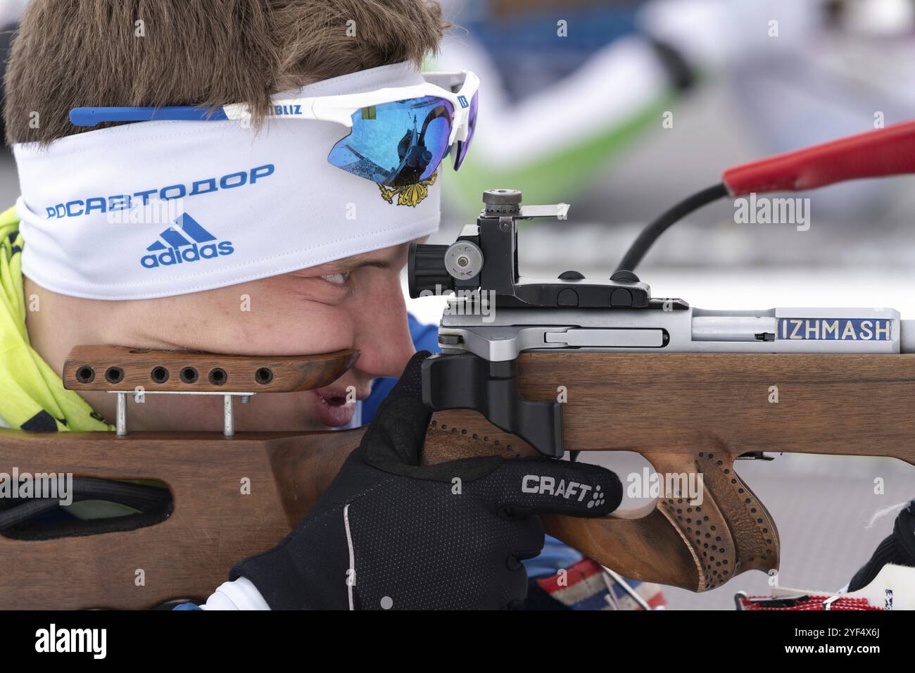 Close-up view sportsman biathlete aiming rifle shooting prone position ...